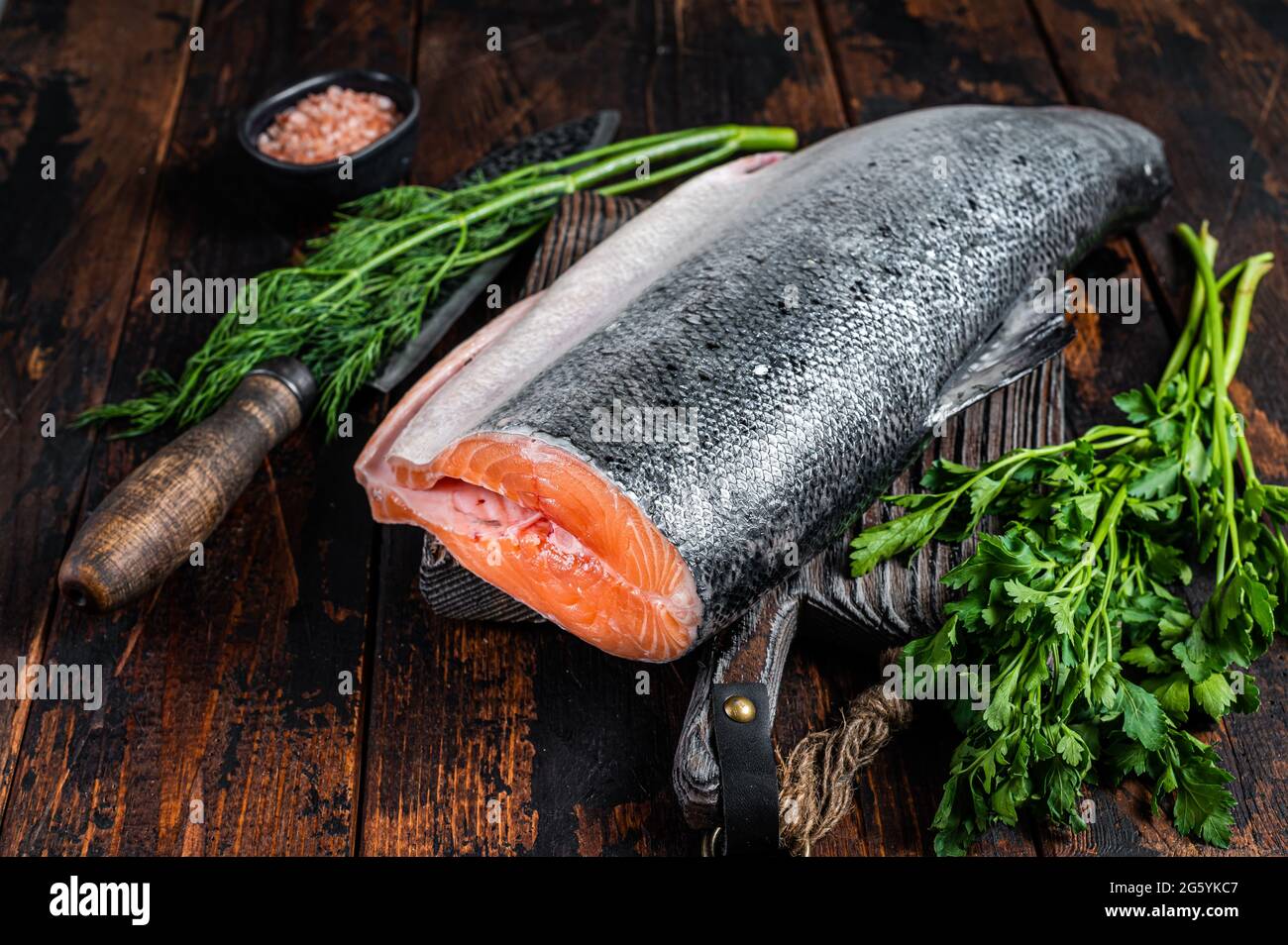 Big piece of Raw cut salmon fish on a wooden cutting board with chef ...