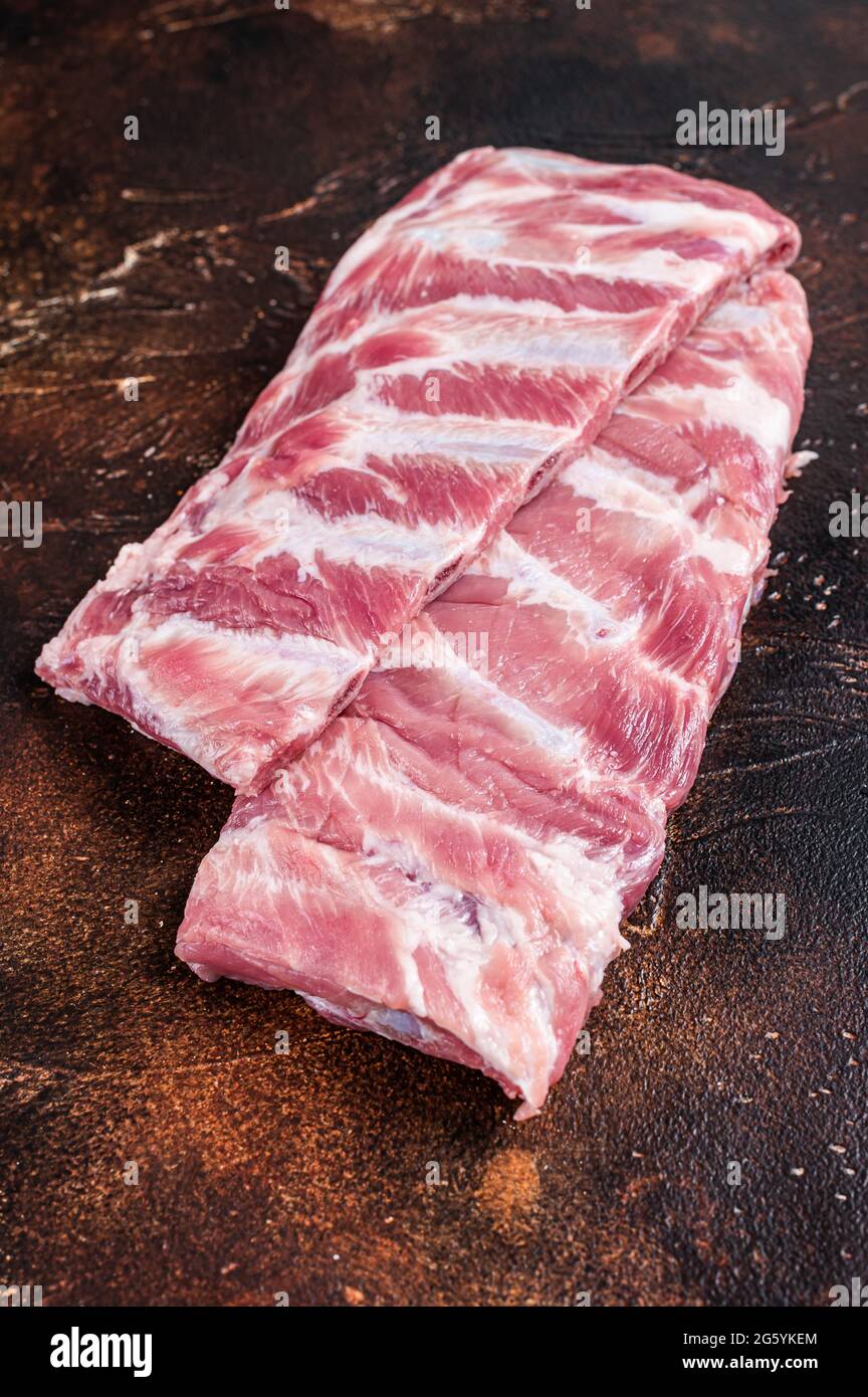 Rack of raw pork spare ribs on butcher table. Dark background. Top view ...