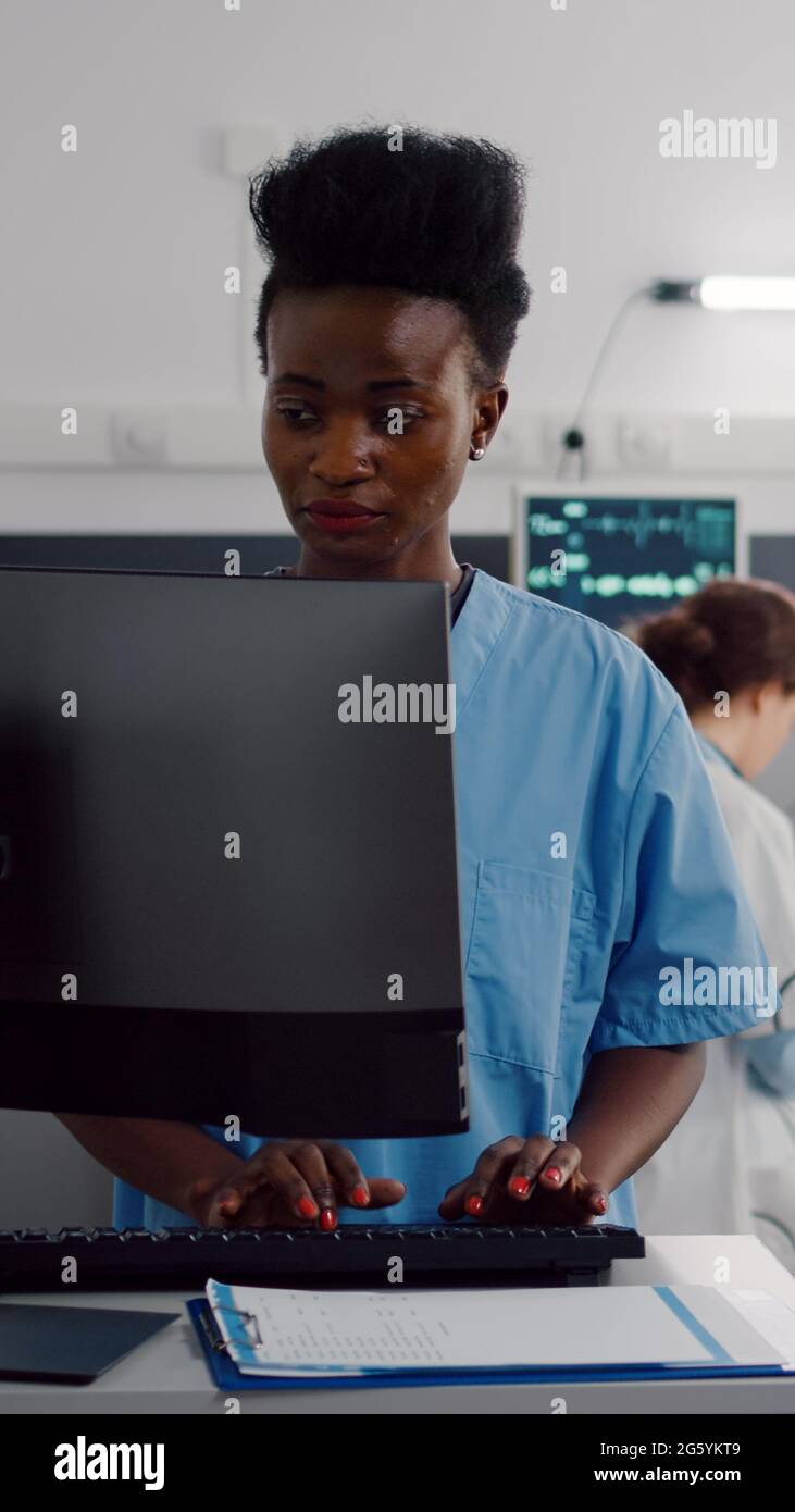 Black assistant typing healdcare treatment on computer while in ...