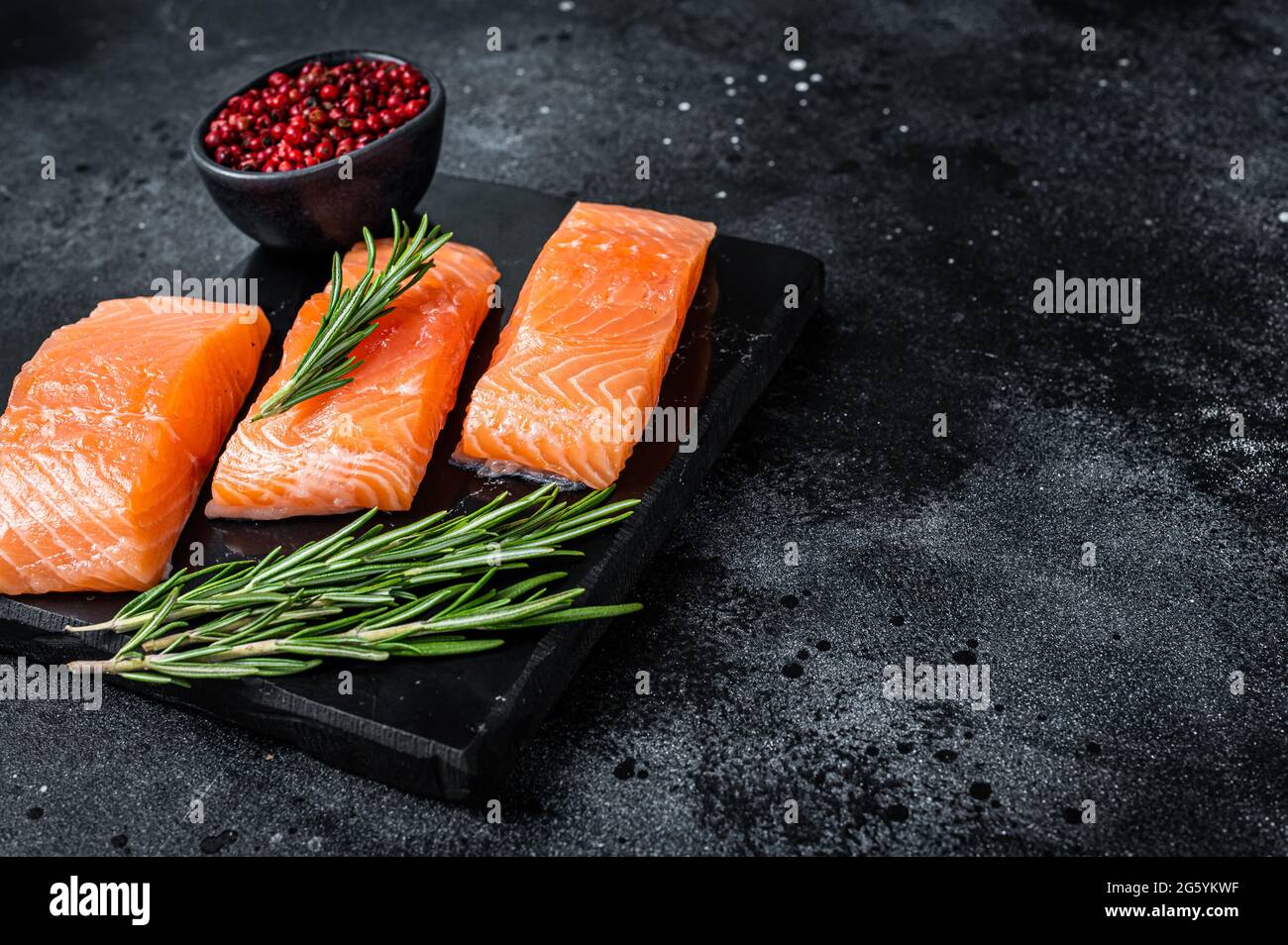 Raw salmon fillet steaks on marble board with herbs. Black background ...