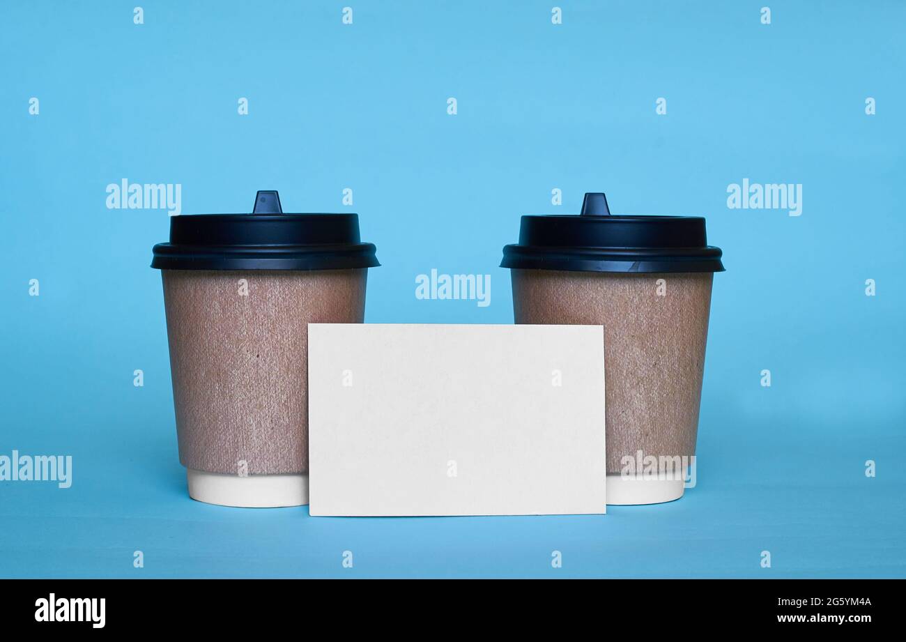 Two paper cups for coffee and a white cardboard card on a blue ...