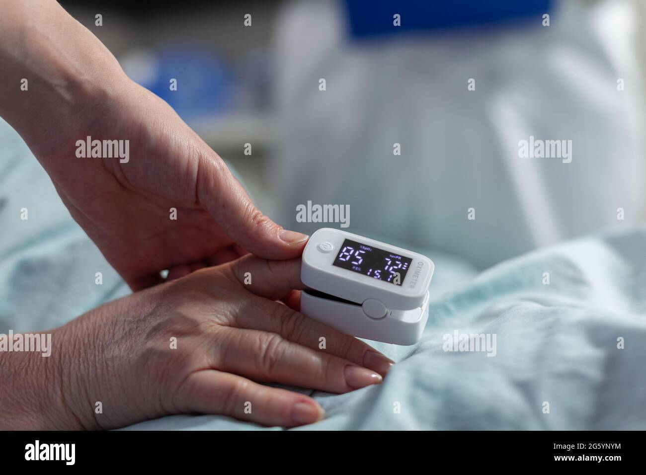 Close up of oxymeter attached on sick senior patient laying in hospital ...