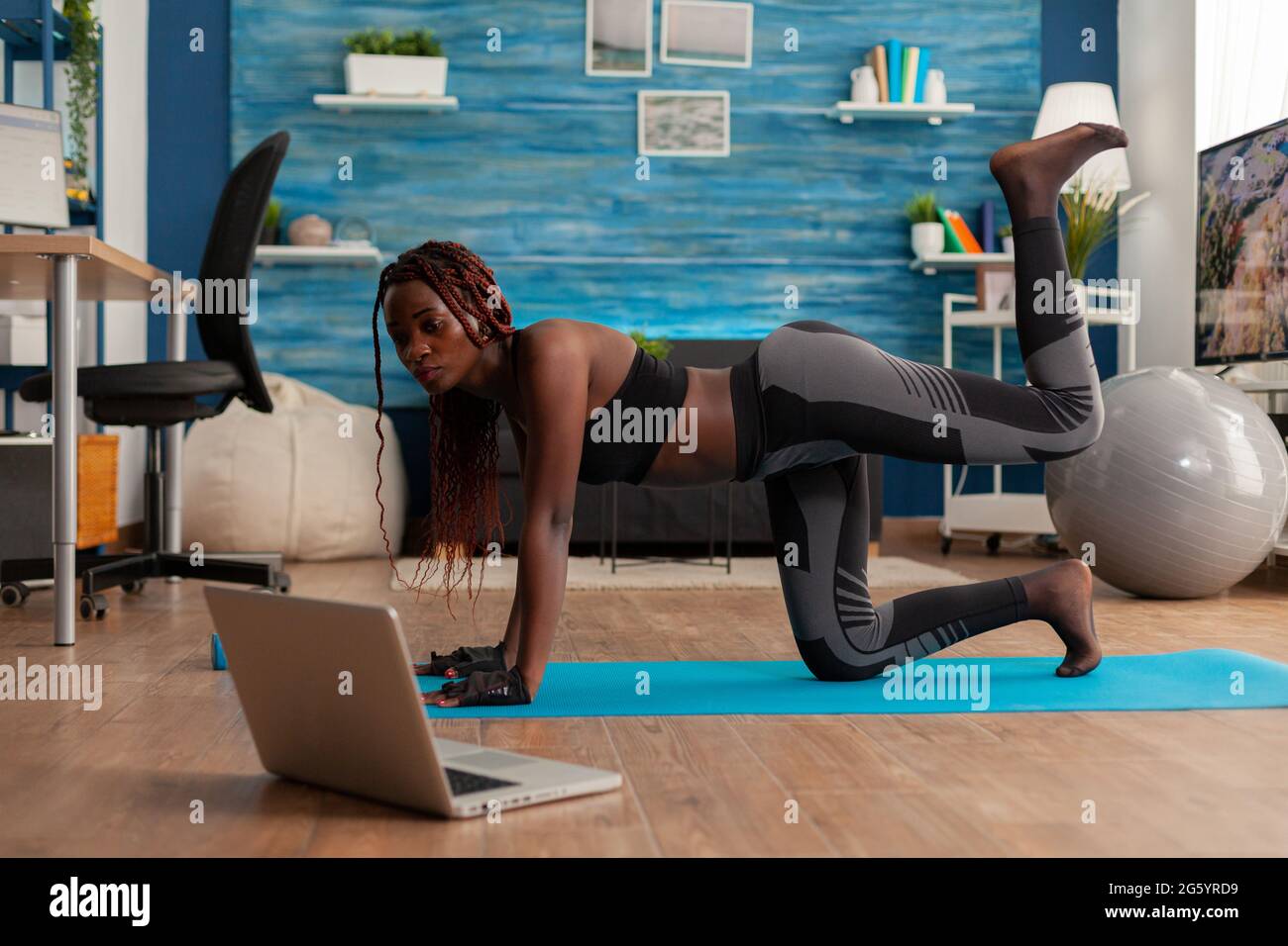 Black woman doing straight- leg donky kick pushing left foot up keeping ...