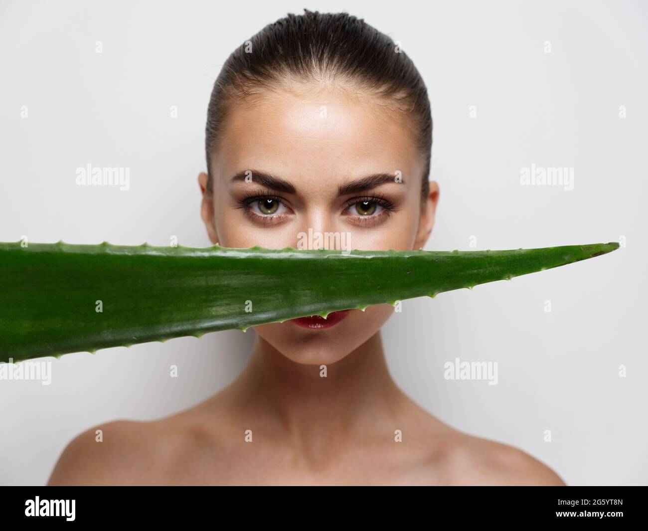 woman hiding behind green aloe leaf clean skin cosmetology natural look ...