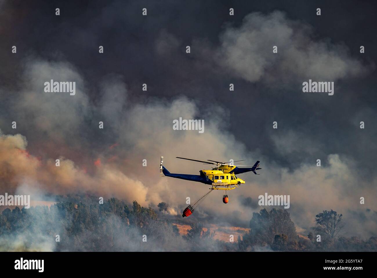 Two helicopters with bambi bucket team working on fire extinction Stock ...