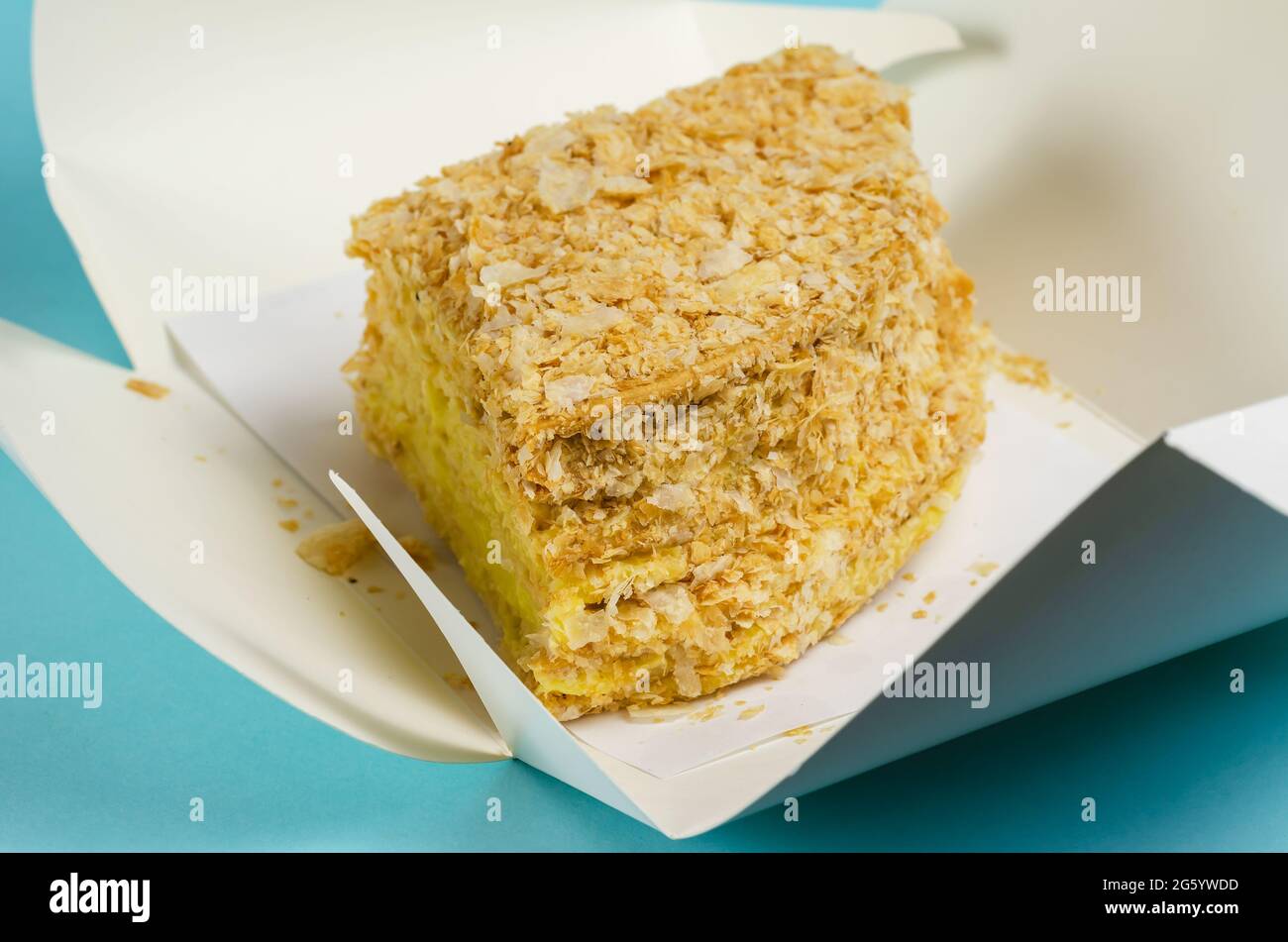 The cake is packaged in a white paper box on a light blue background ...