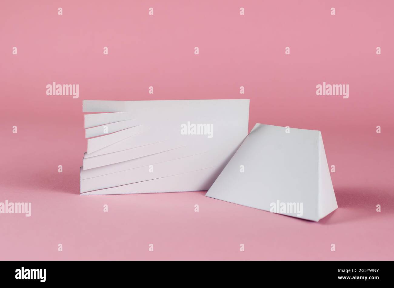 White blank rectangle with cut strips and trapezoid on pink background ...