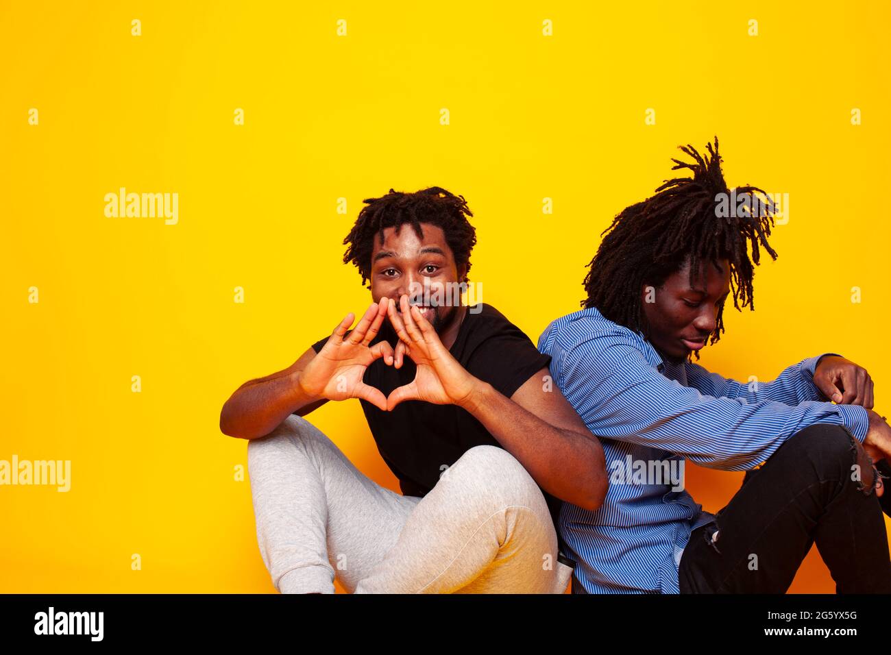 two african american guys posing cheerful together on yellow background ...