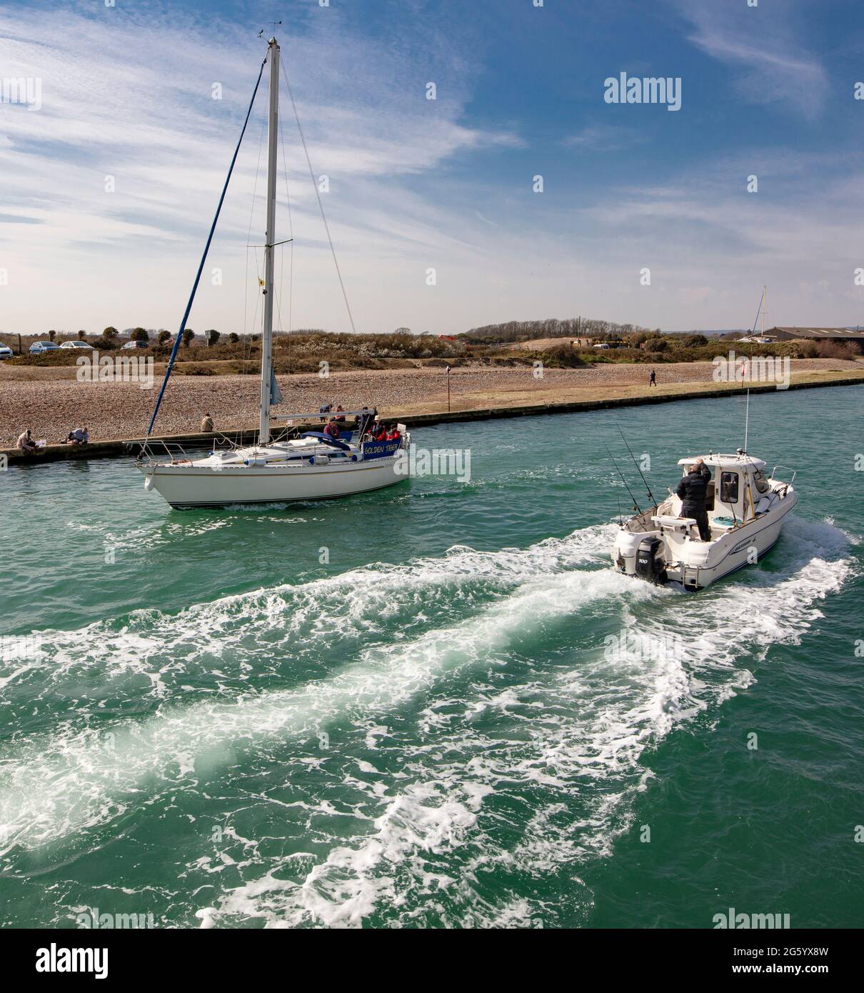 A motor boat trailing a wake and a sailing yacht passing at the mouth ...