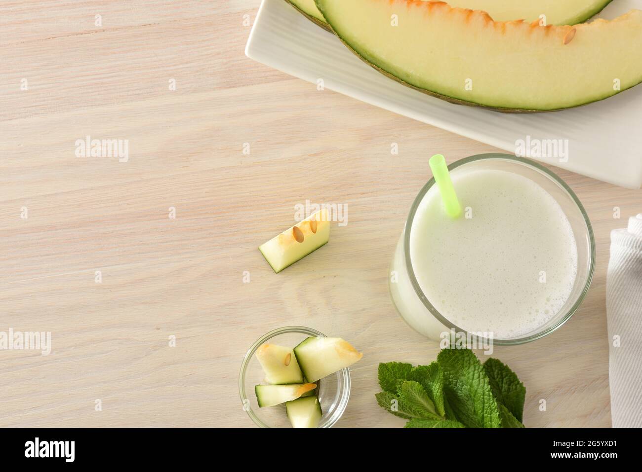 Glass with natural melon milk shake on white wooden kitchen bench with ...