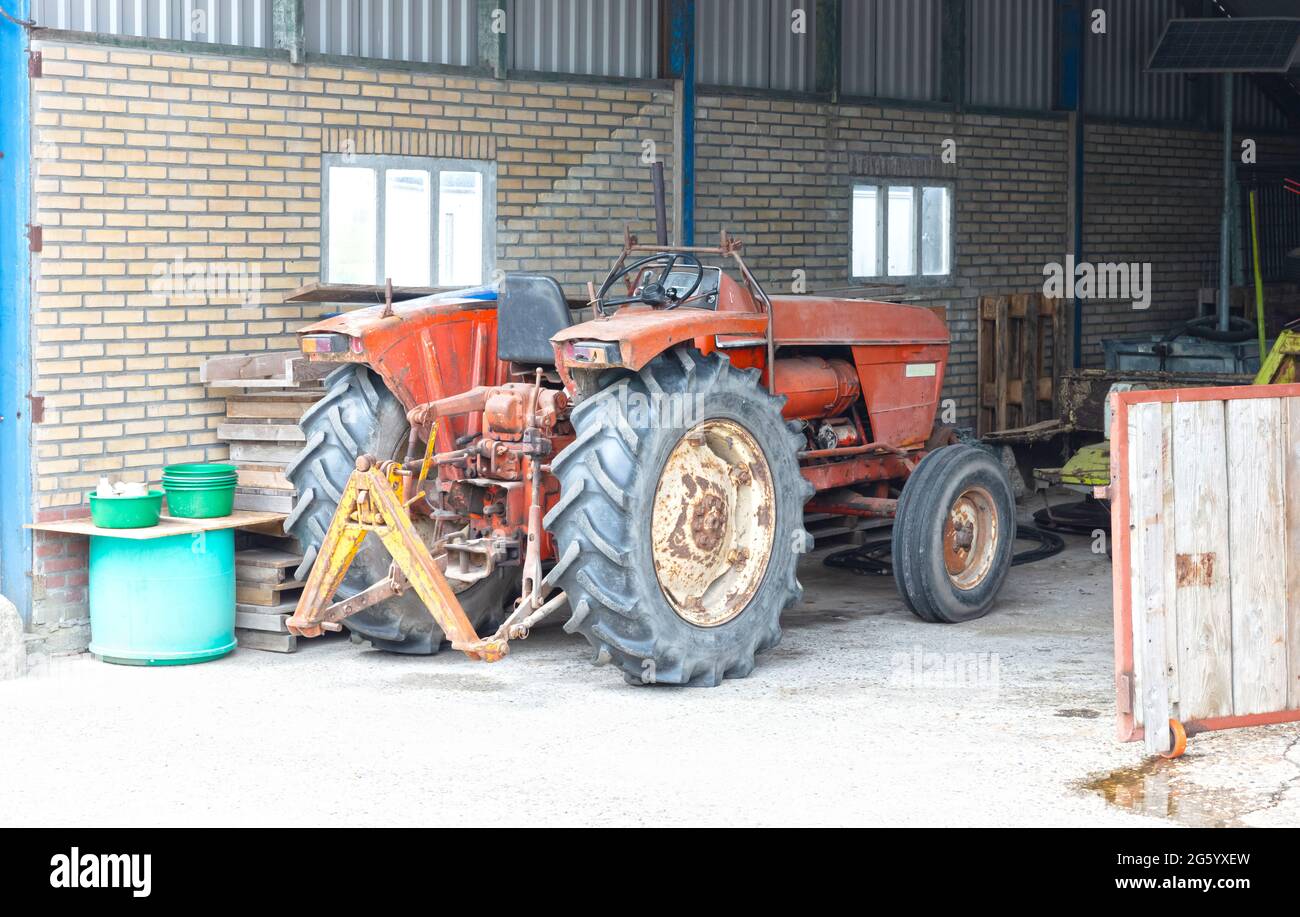 Old red tractor inside garage, still in use Stock Photo - Alamy