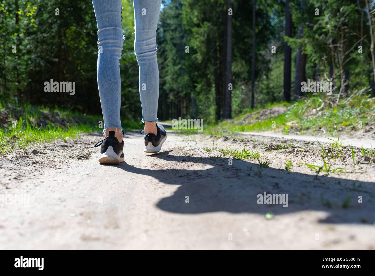 Rear view photo of female tourist legs with sneakers walking in a ...
