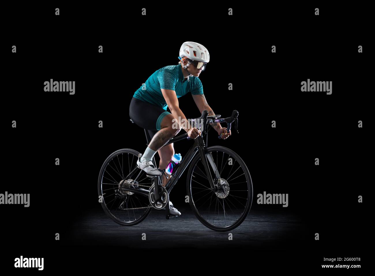 Professional young female cycler on road bike isolated over black ...