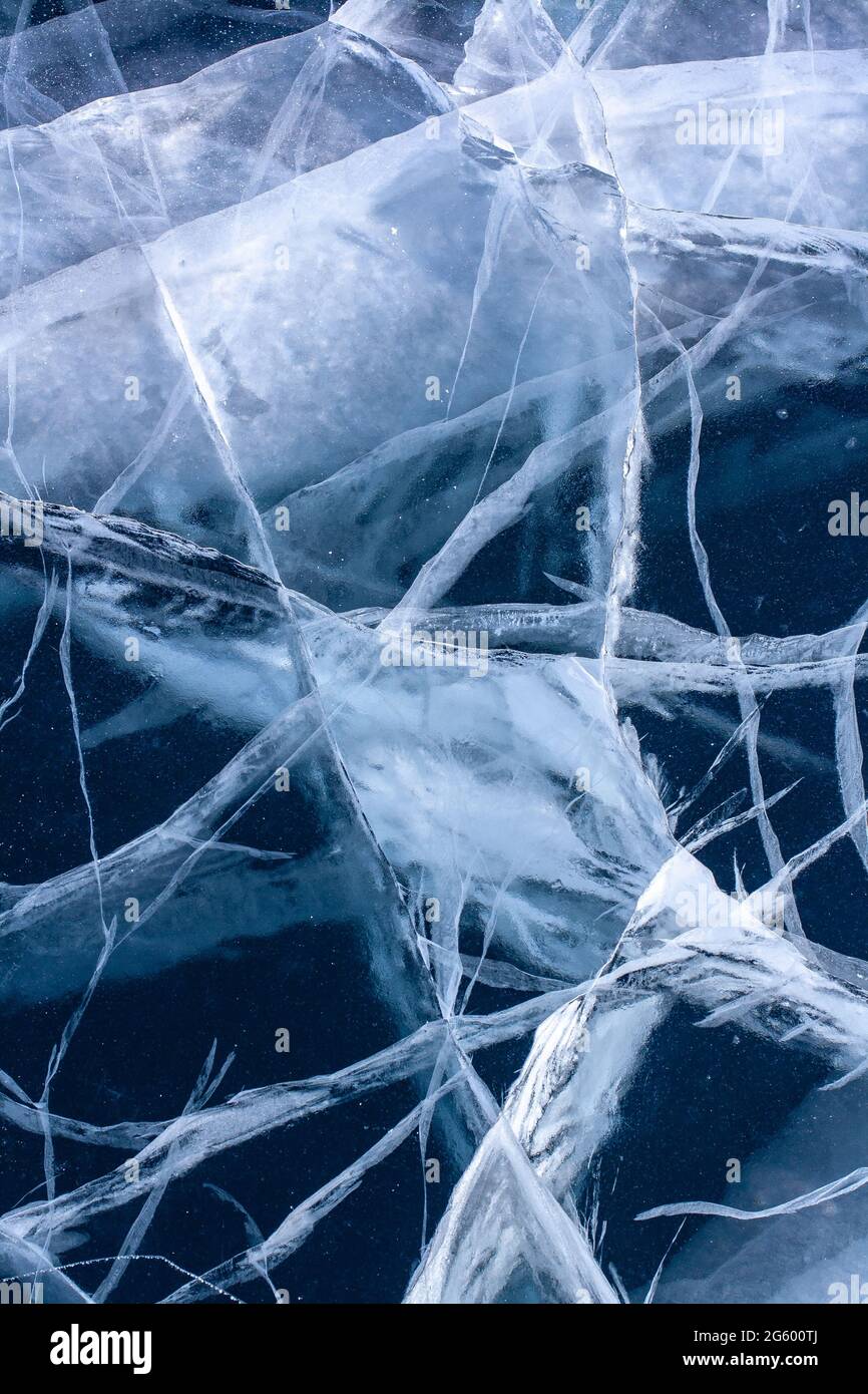 White deep cracks in transparent clear ice. Lake with blue ice ...