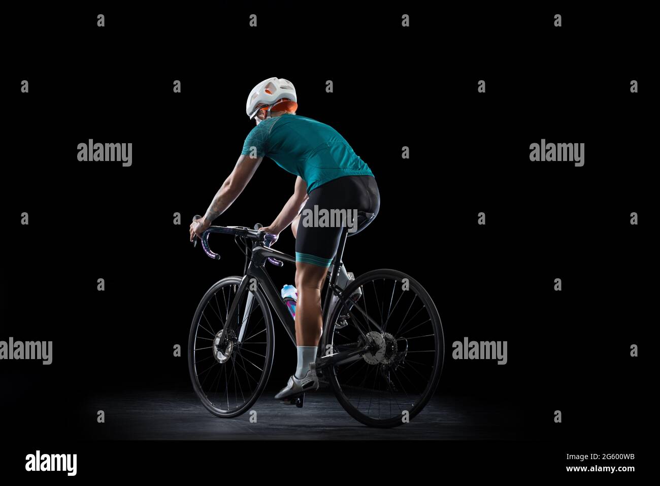 Professional young female cycler on road bike isolated over black ...