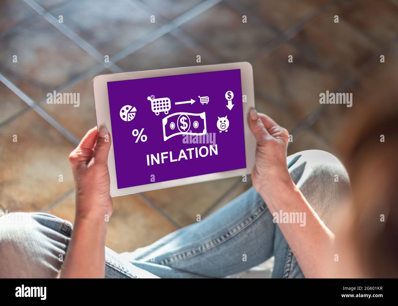 Woman sitting on the floor with a tablet showing inflation concept ...
