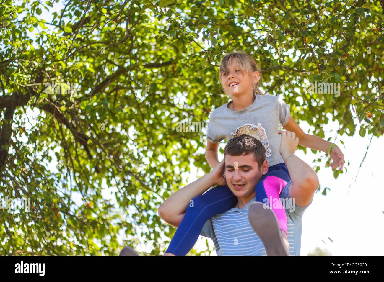 Defocused brother riding sister on back. Portrait of happy girl on man ...