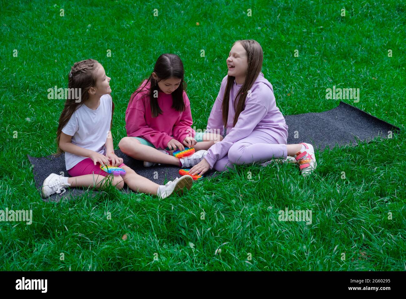three teenage girls play with trendy sensory toy pop it outdoors on ...