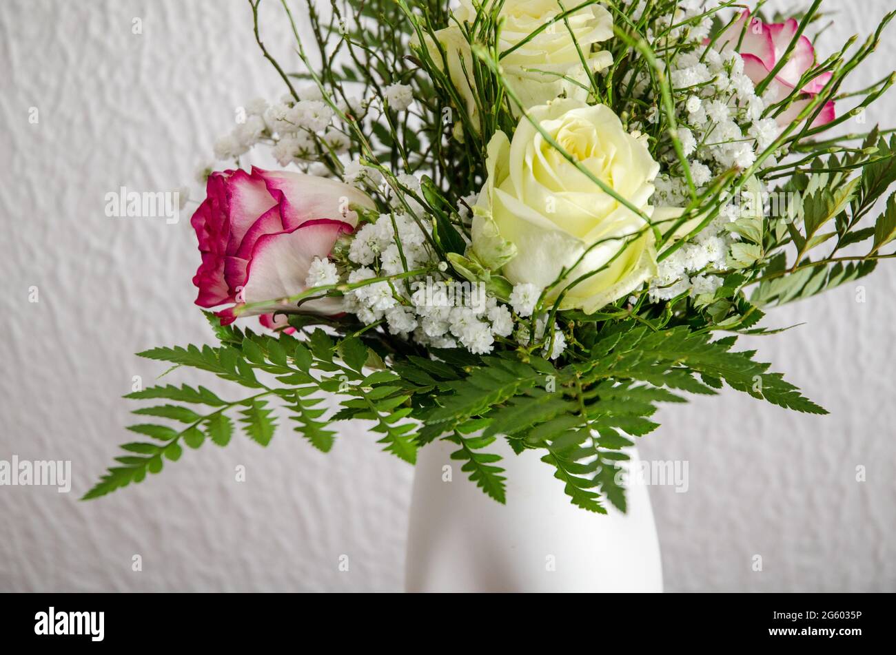 Close-up still life of a flower arrangement with roses in a white vase ...