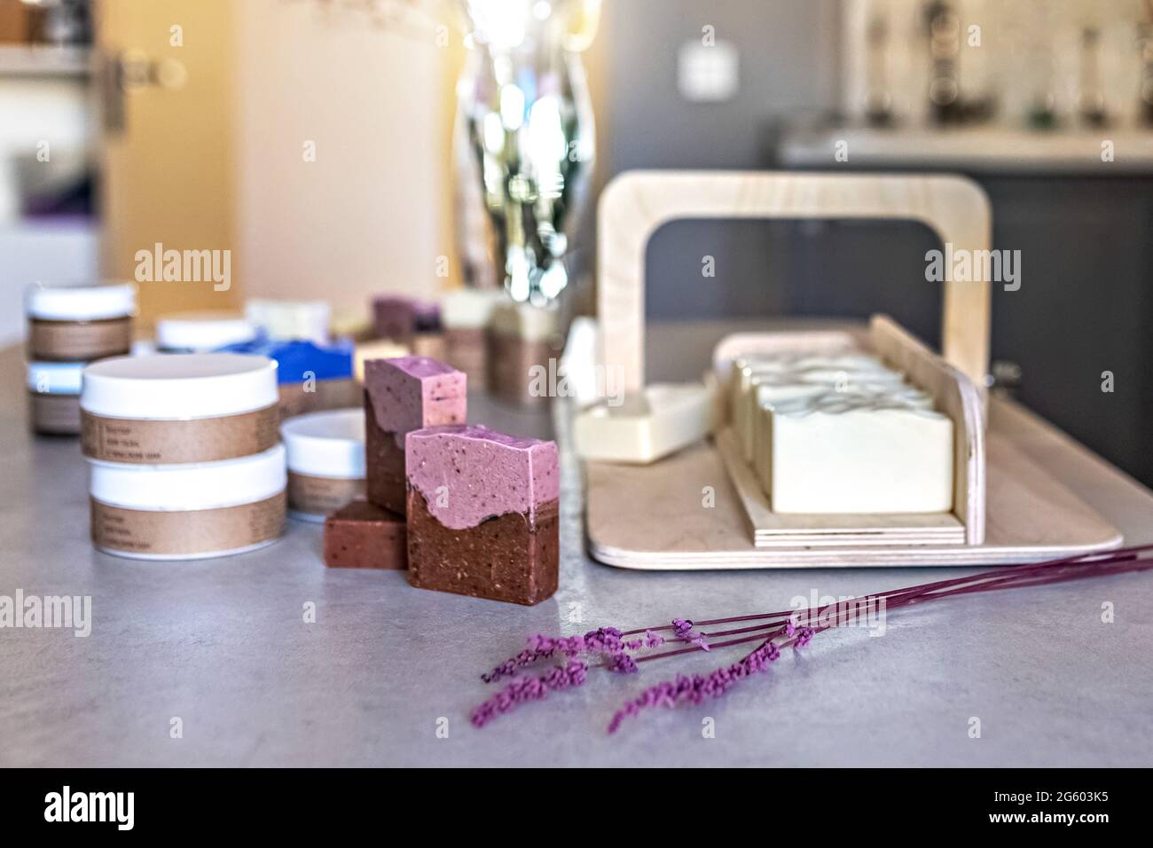 A soap-maker girl holds a piece of freshly brewed handmade soap in her ...