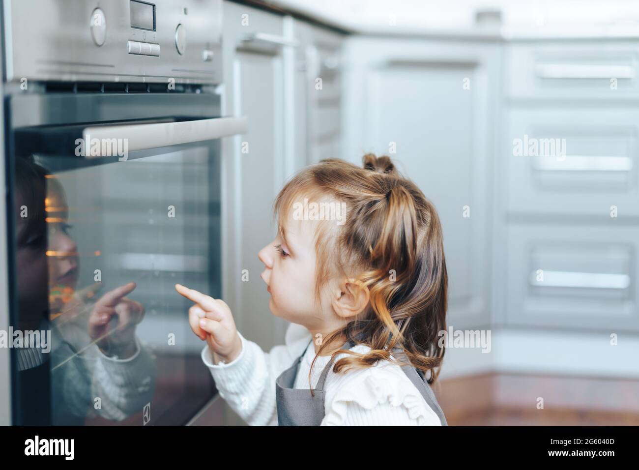 Little girl looking at oven, waiting prepare of food Stock Photo - Alamy