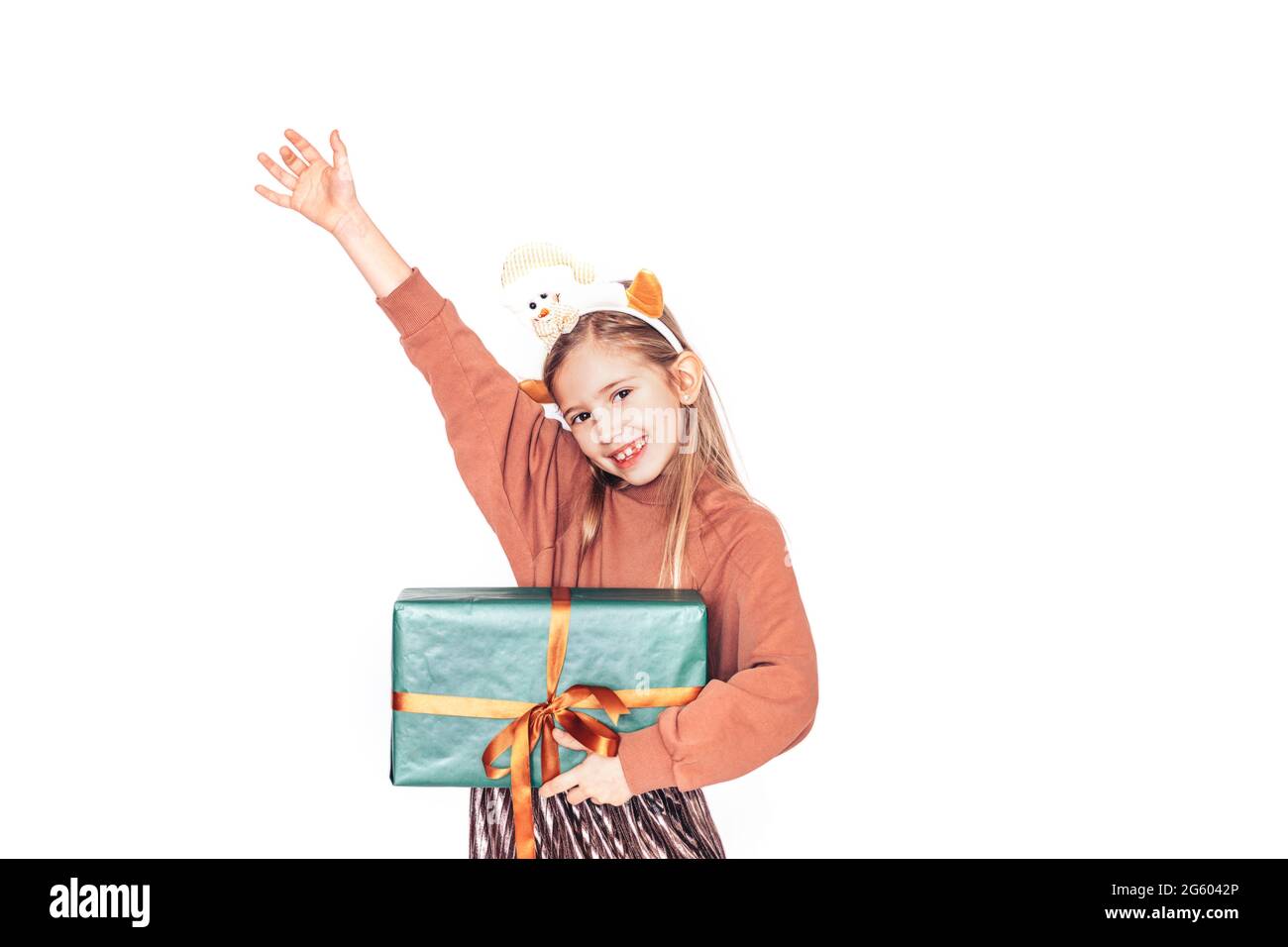 Girl holding gift with one hand and raised the other up against white ...