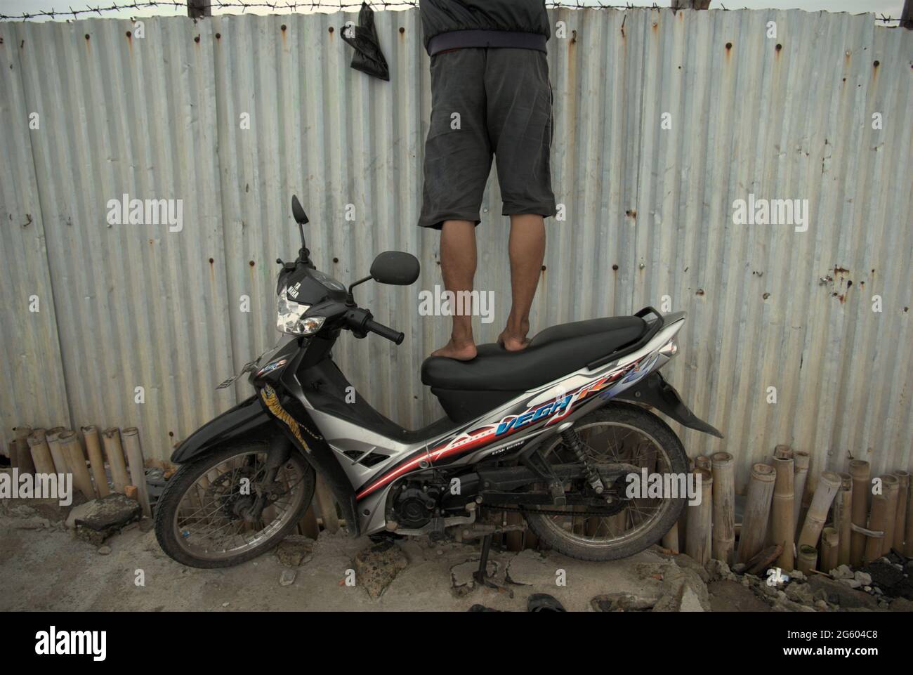 A recreational fisher standing on motorcycle to fish on a pond located ...