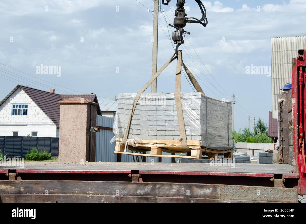 Unloading paving slabs from a truck. Men unload paving slabs using a ...