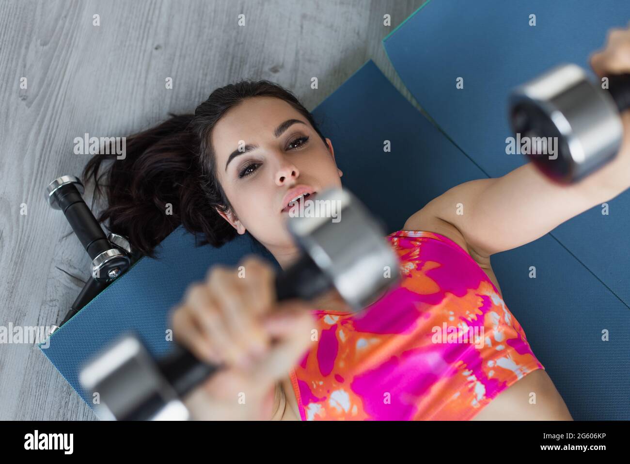 top view of young woman in sportswear lying on fitness mats and doing ...