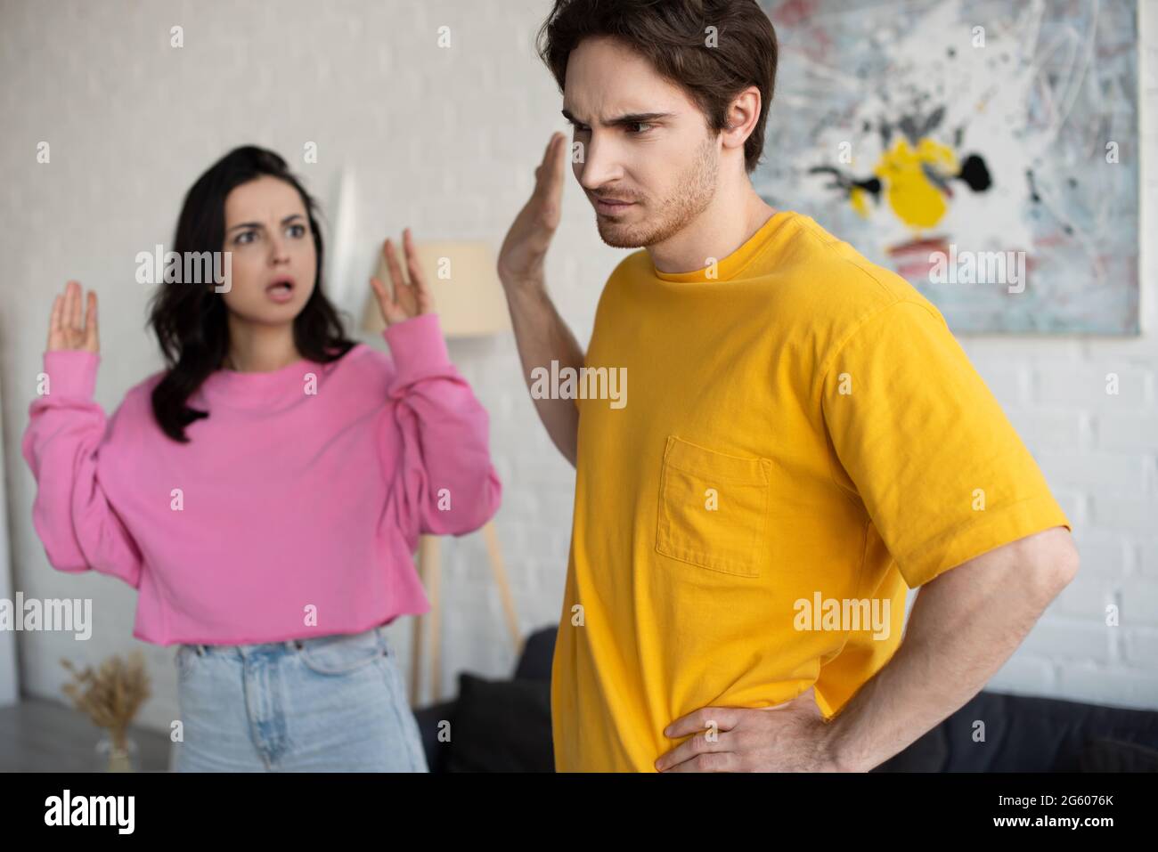 angry young woman shouting with hands in air near boyfriend with refuse ...