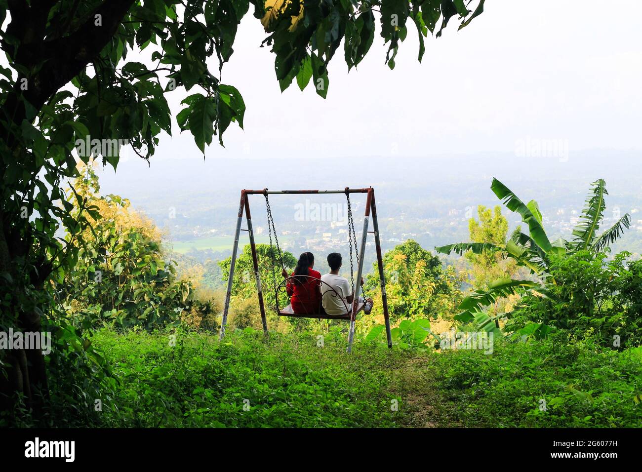 Romantic couple swinging on swings over the green mountain landscape ...