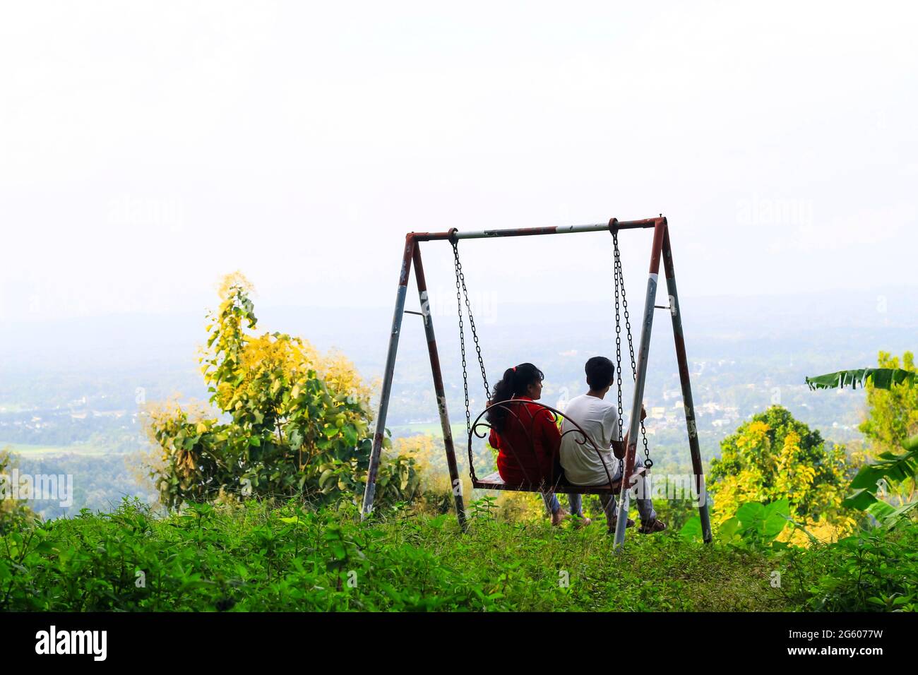Romantic couple swinging on swings over the green mountain landscape ...