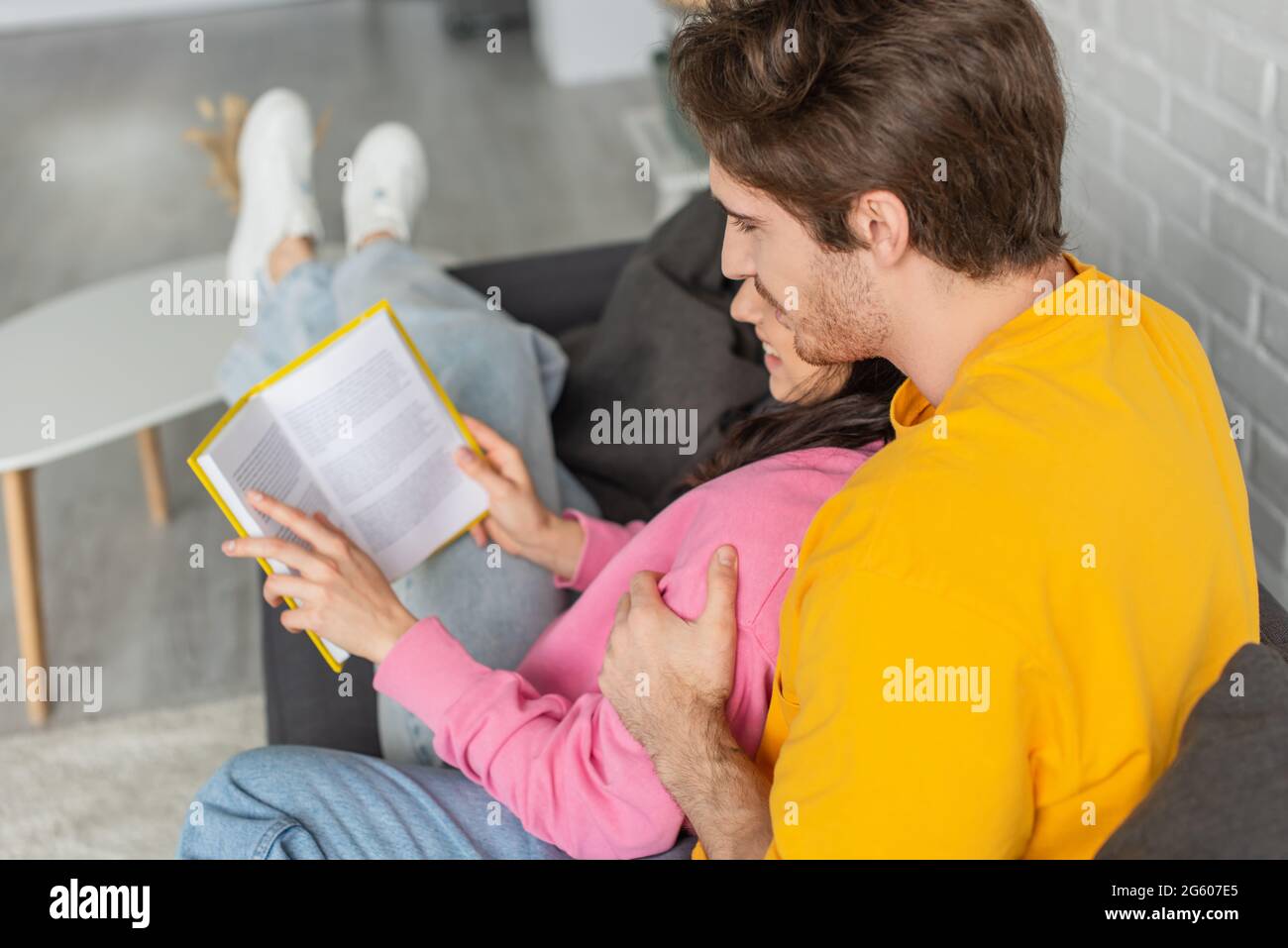 happy young couple hugging and reading book in living room Stock Photo ...