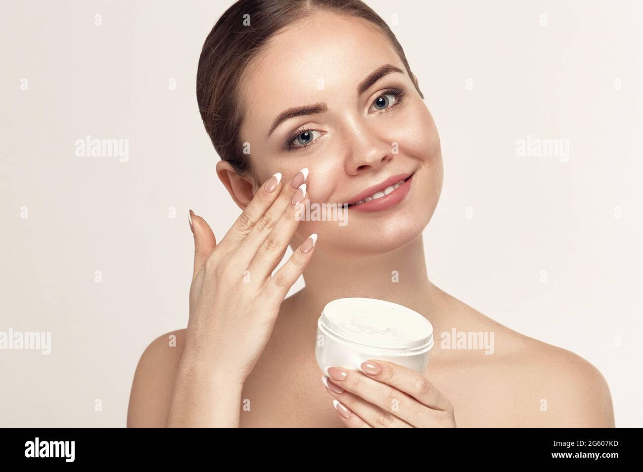 beautiful model applying cosmetic cream treatment on her face on white ...
