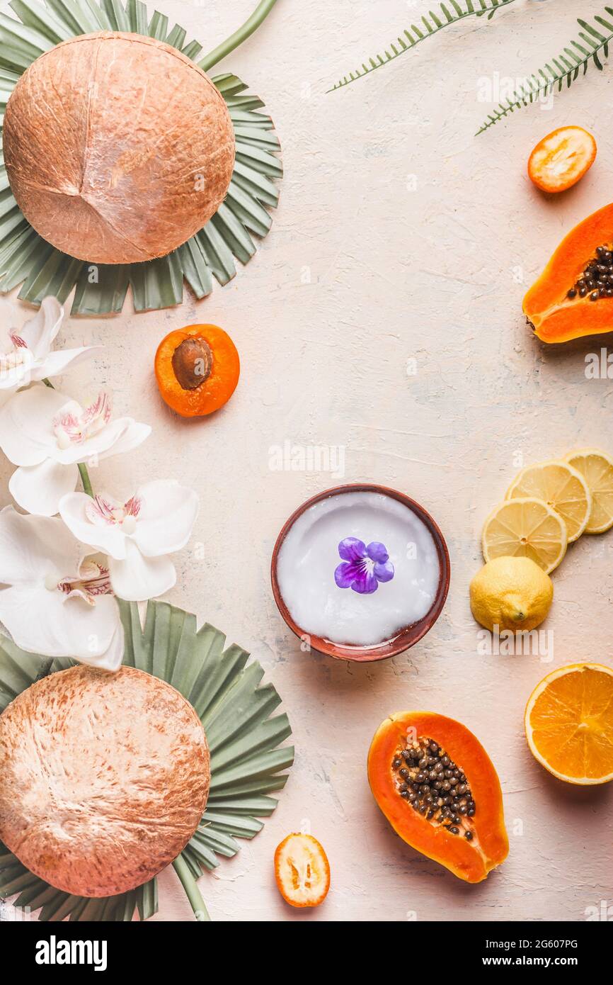Coconut oil in a coconut shell and tropical fruits are arranged in a ...