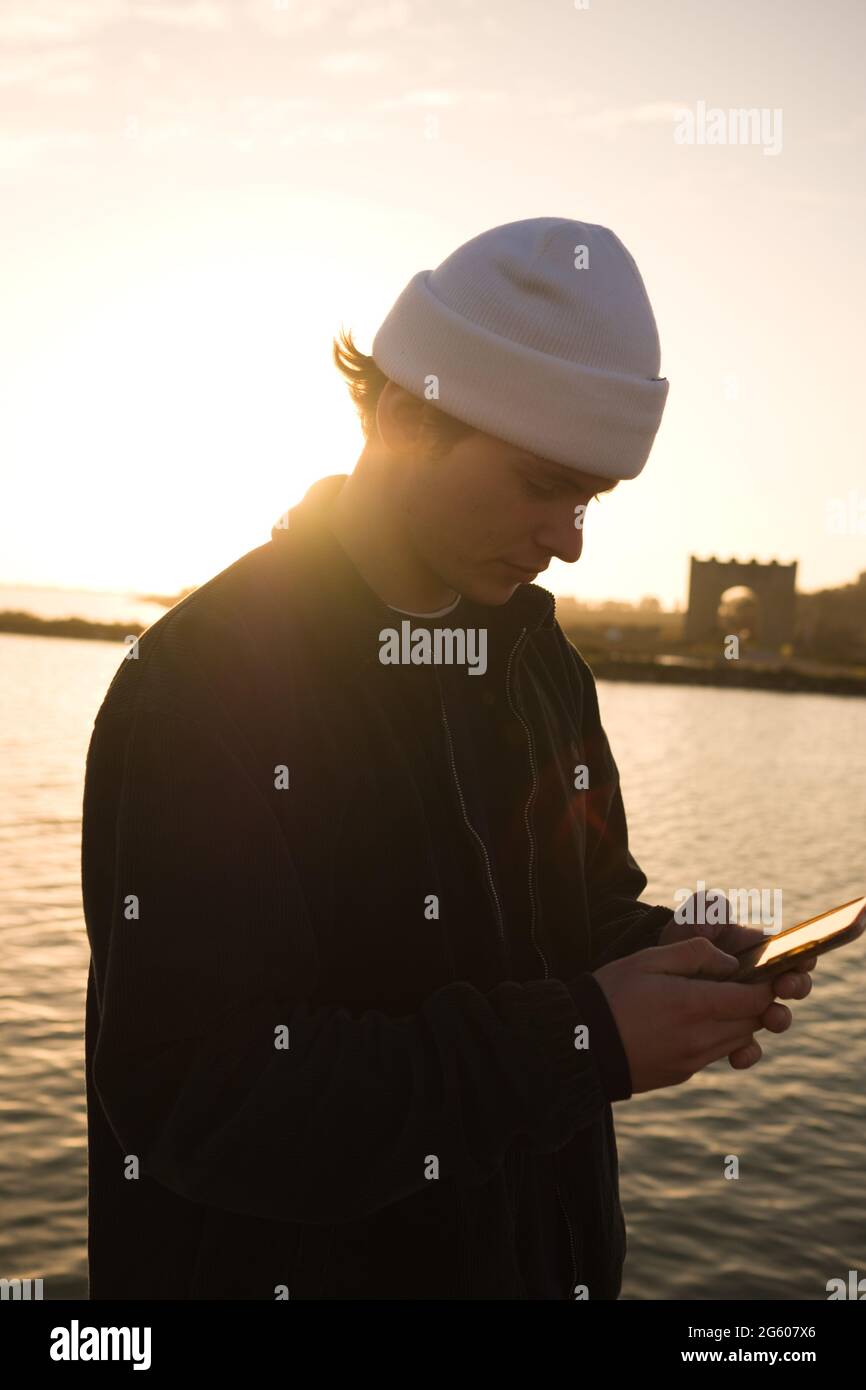 side profile of twenty year old man with cream beanie hat standing by a ...
