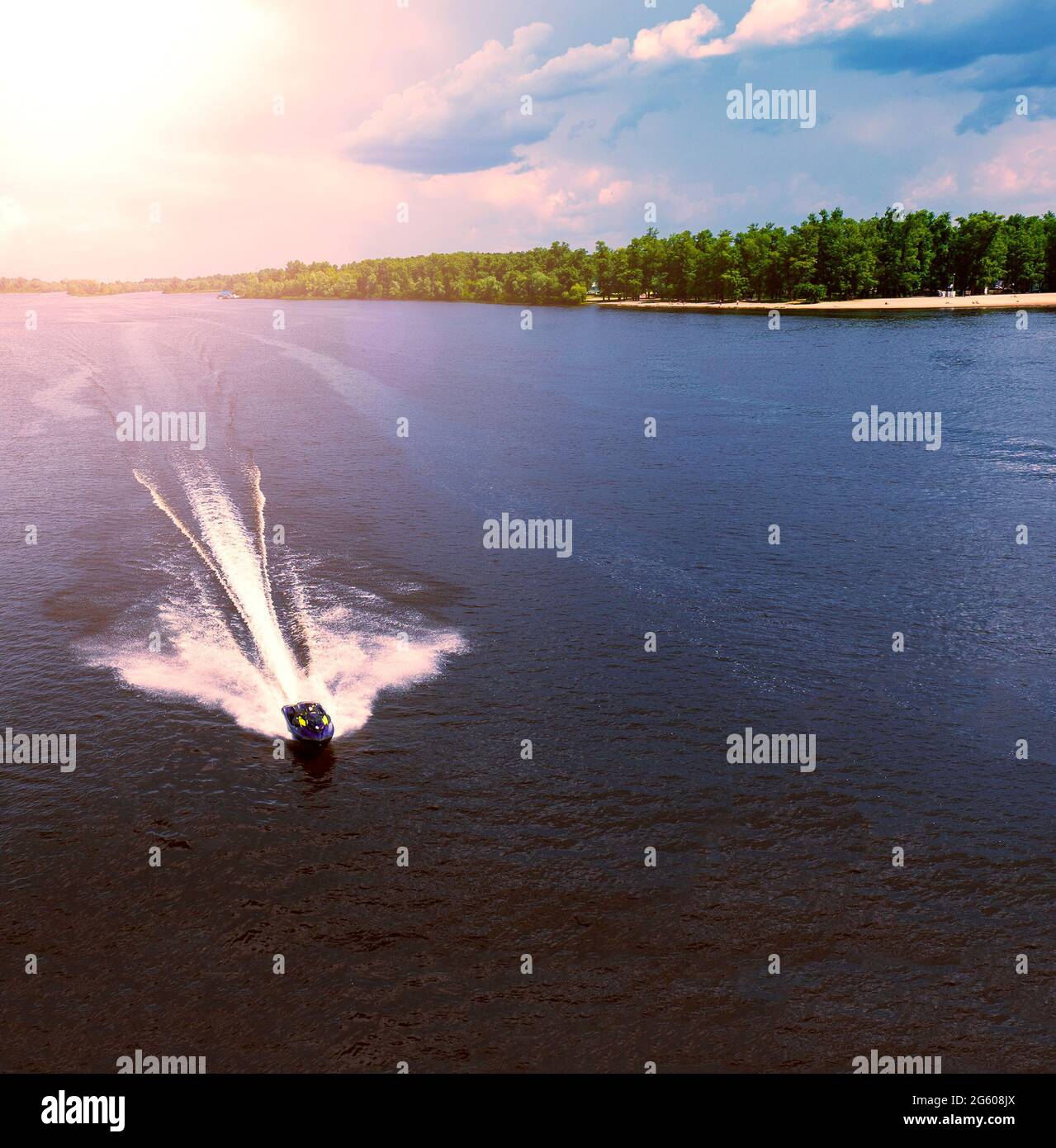 Top view of a jet ski in the river above it the orange sun shines ...
