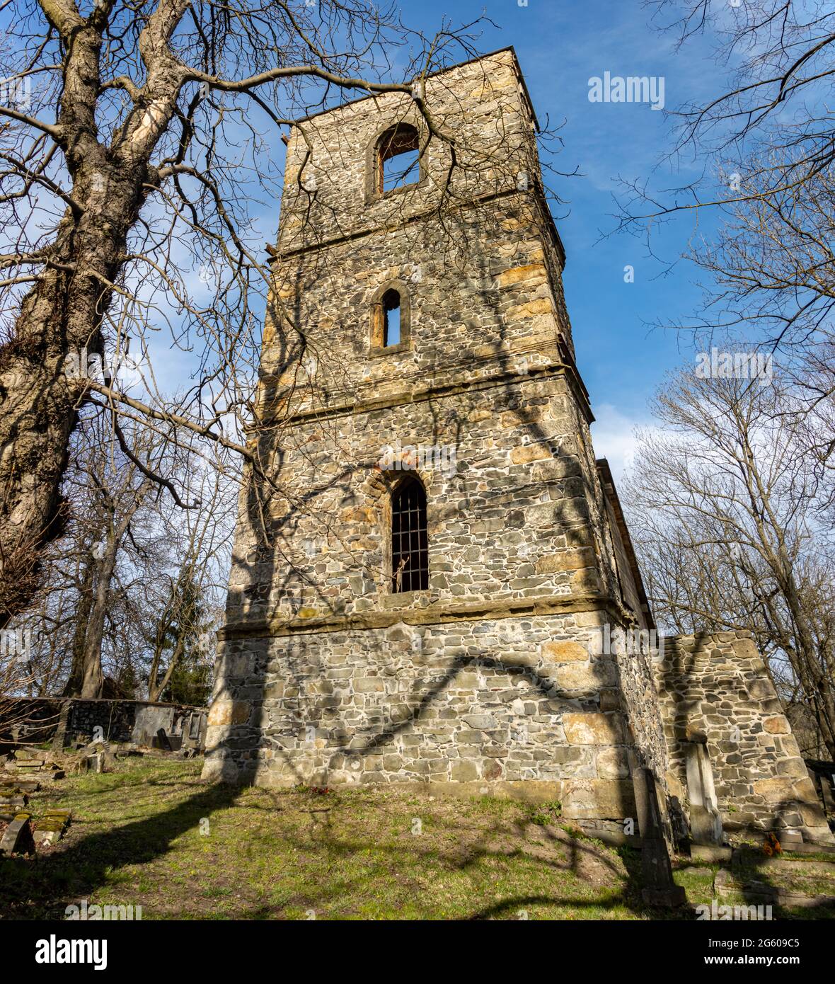A half-demolished stone church behind the enclosure wall with blue sky ...