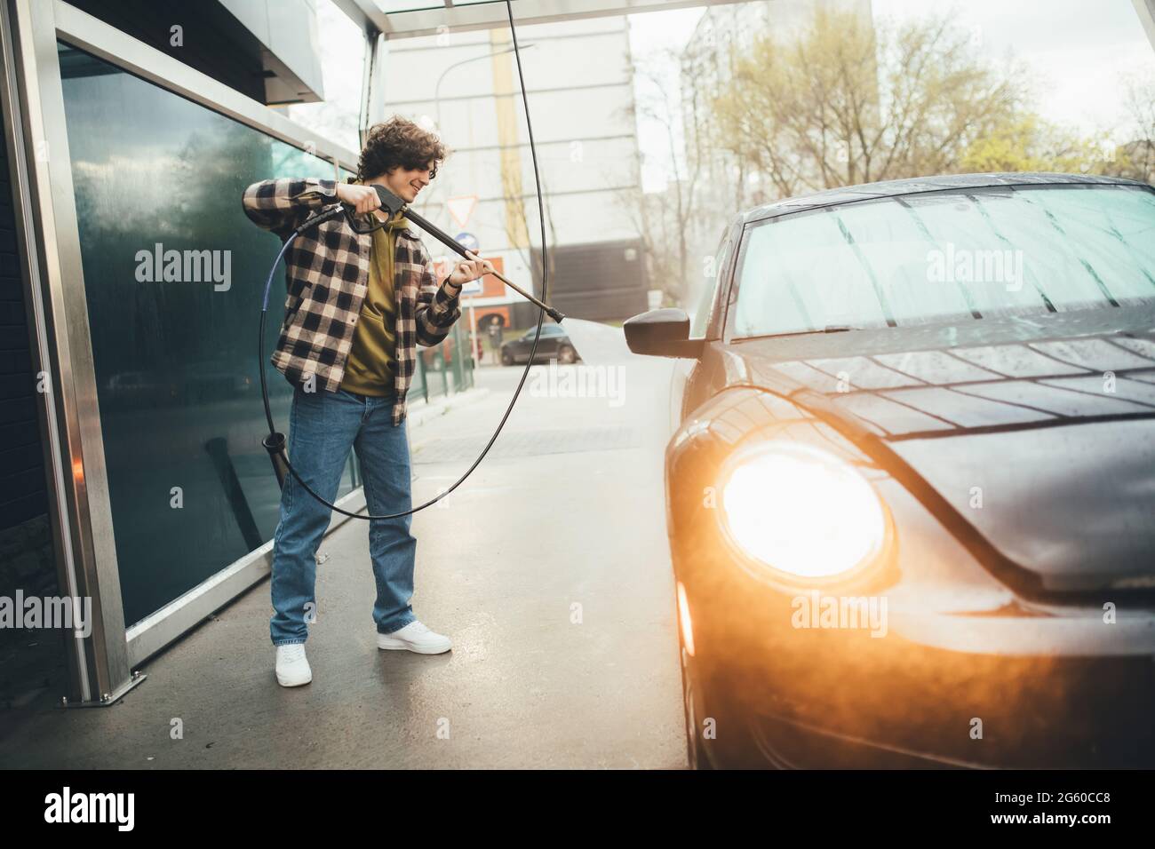Side view of smiling man washing car on self service wash Stock Photo ...