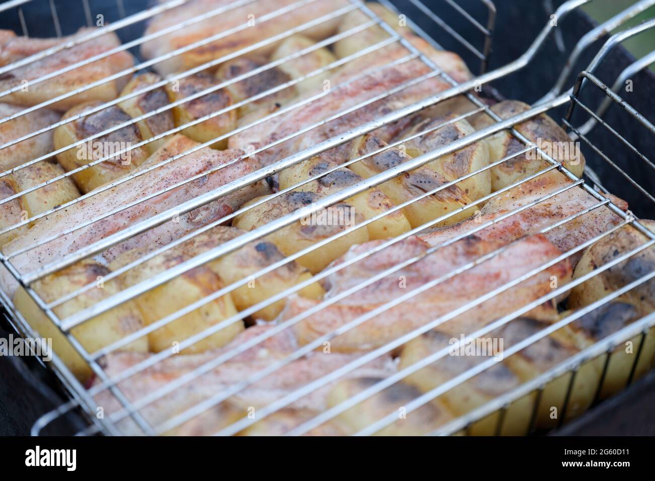 Roast pork and potatoes on wire rack over fire closeup Stock Photo - Alamy