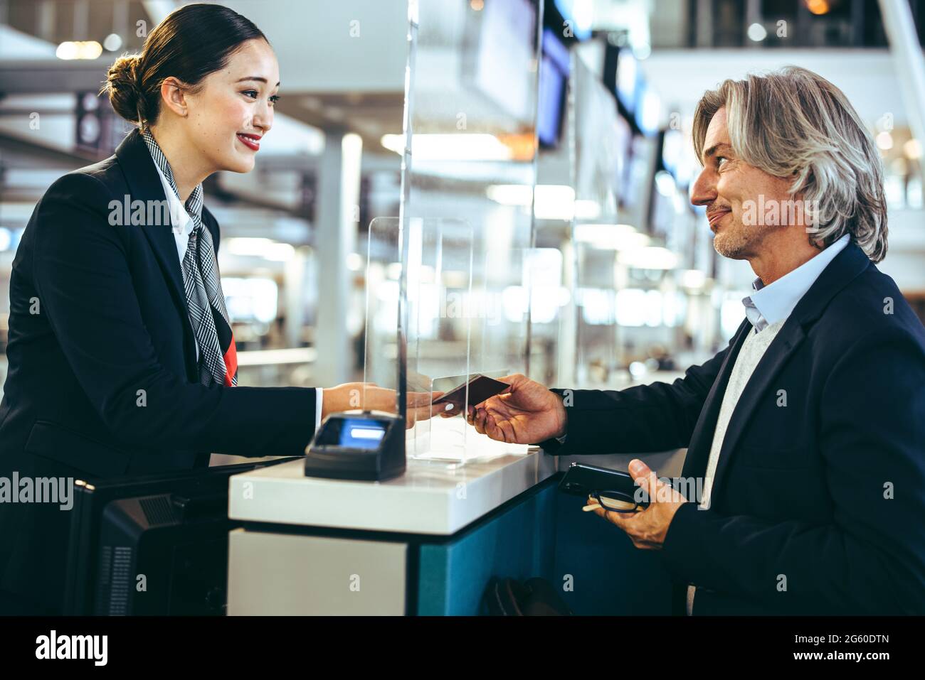 Mature businessman doing check-in at airline check-in counter at ...