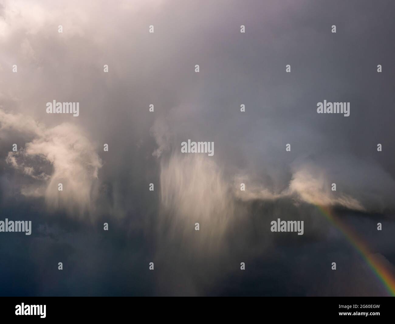 Dark heavy storm clouds with a rainbow on the edge Stock Photo - Alamy