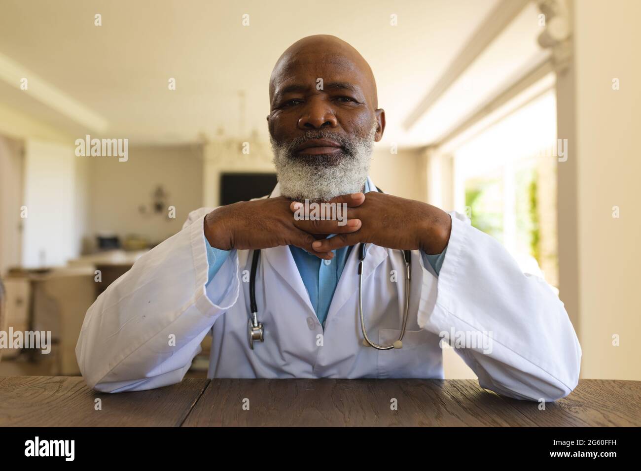 Portrait of senior african american male doctor in lab coat sitting at ...