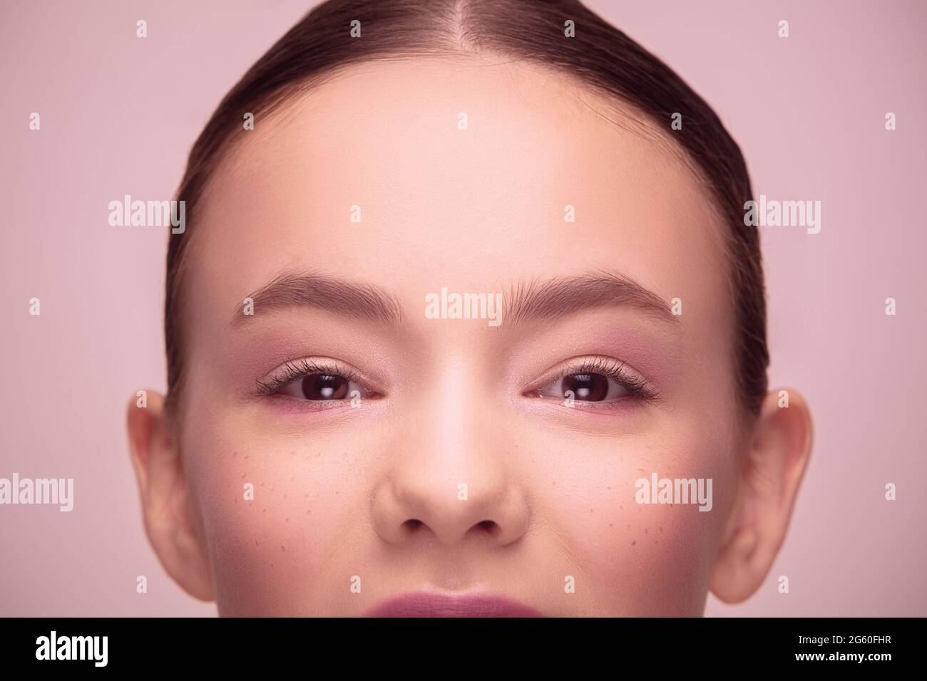 close-up beautiful young girl isolated on light pink studio background ...