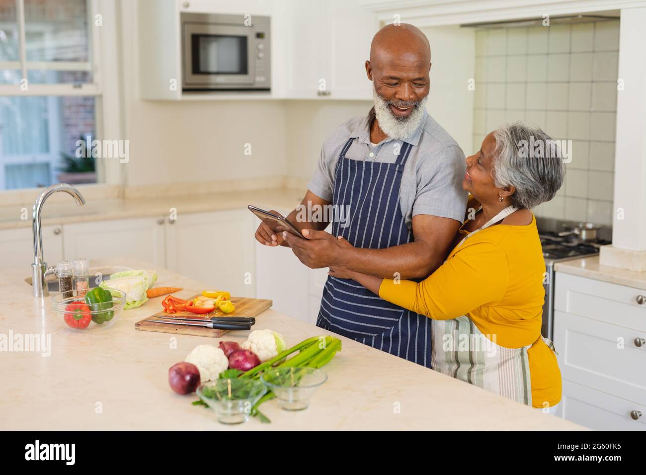 Senior african american couple cooking together in kitchen using tablet ...