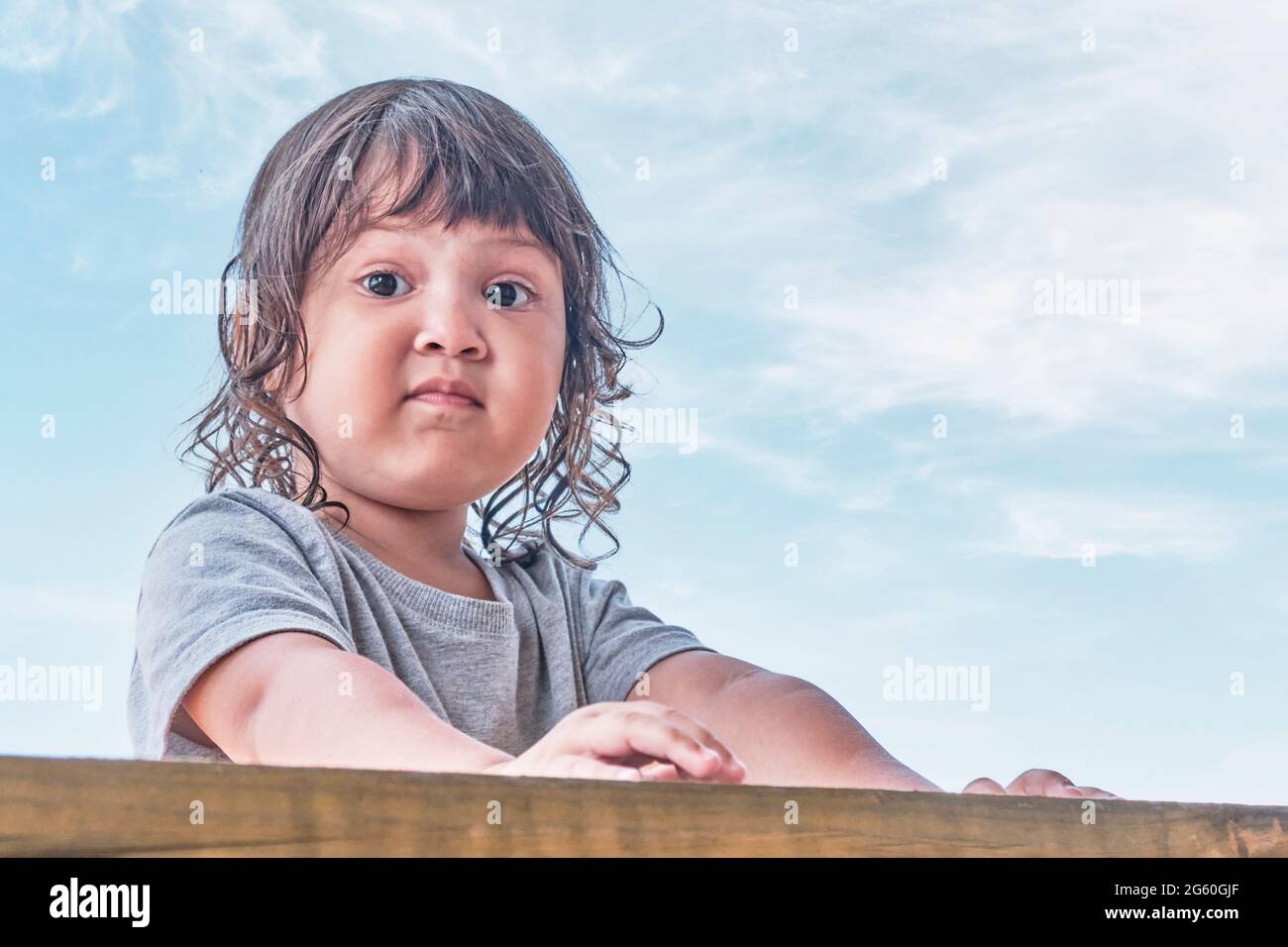 Portrait of little Asian baby girl with black hair looking at camera on ...