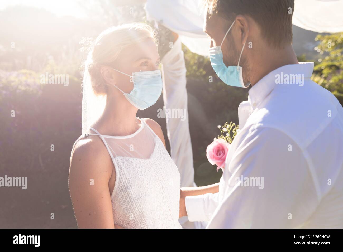 Happy caucasian bride and groom getting married wearing face masks and ...
