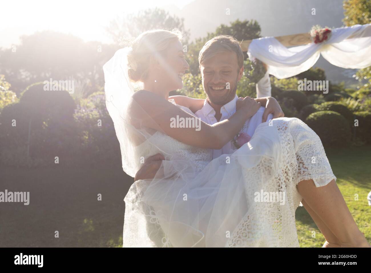 Happy caucasian bride and groom getting married, groom carrying bride ...