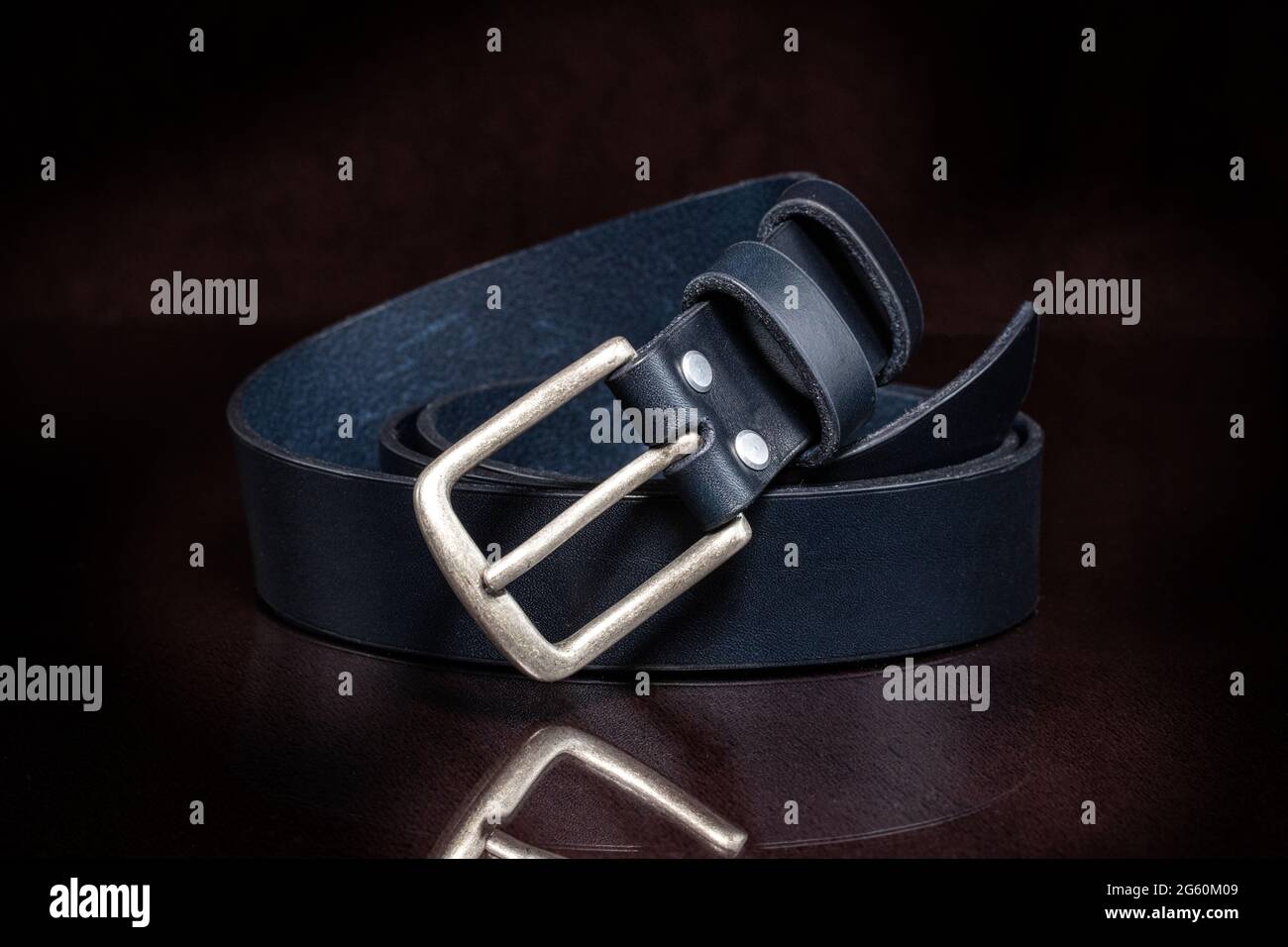 Black leather belt with a metal buckle on a dark background close-up ...