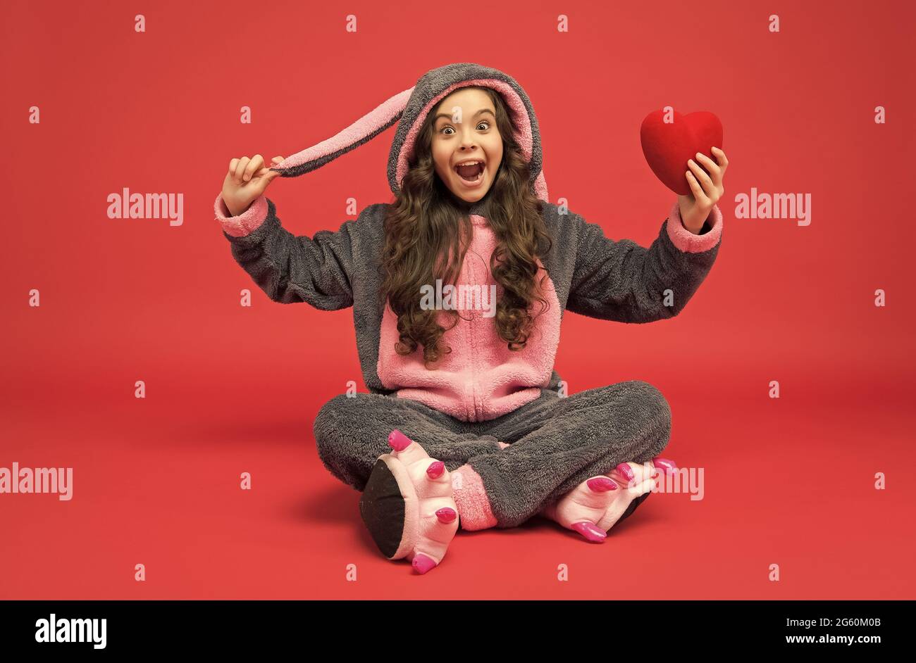 Happy little girl hold red heart love symbol wearing bunny pajamas for ...